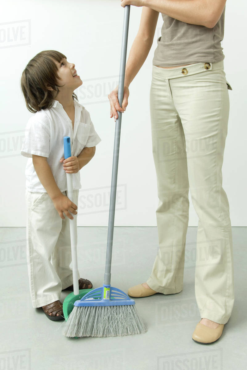 Little boy helping his mother sweep the floor, cropped view - Royalty ...
