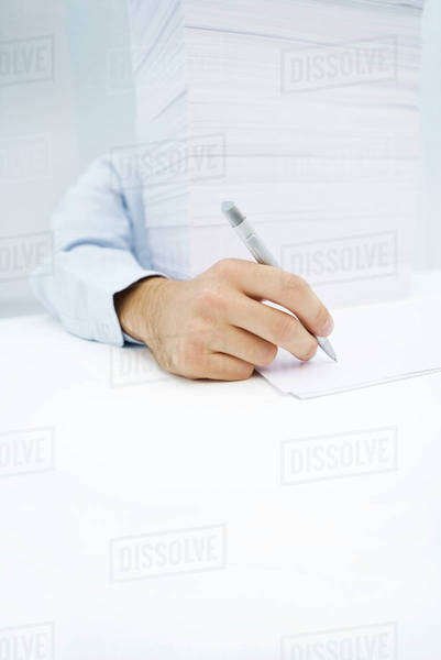 Arm reaching around massive stack of paper to write on a single sheet ...