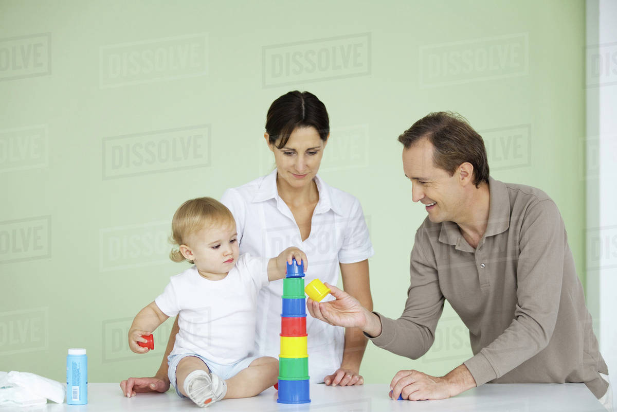 Toddler stacking plastic toys, parents watching - Royalty-free Stock ...