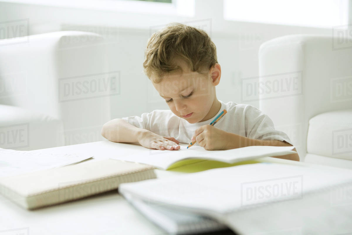 Little boy sitting at coffee table, working on homework - Royalty-free ...