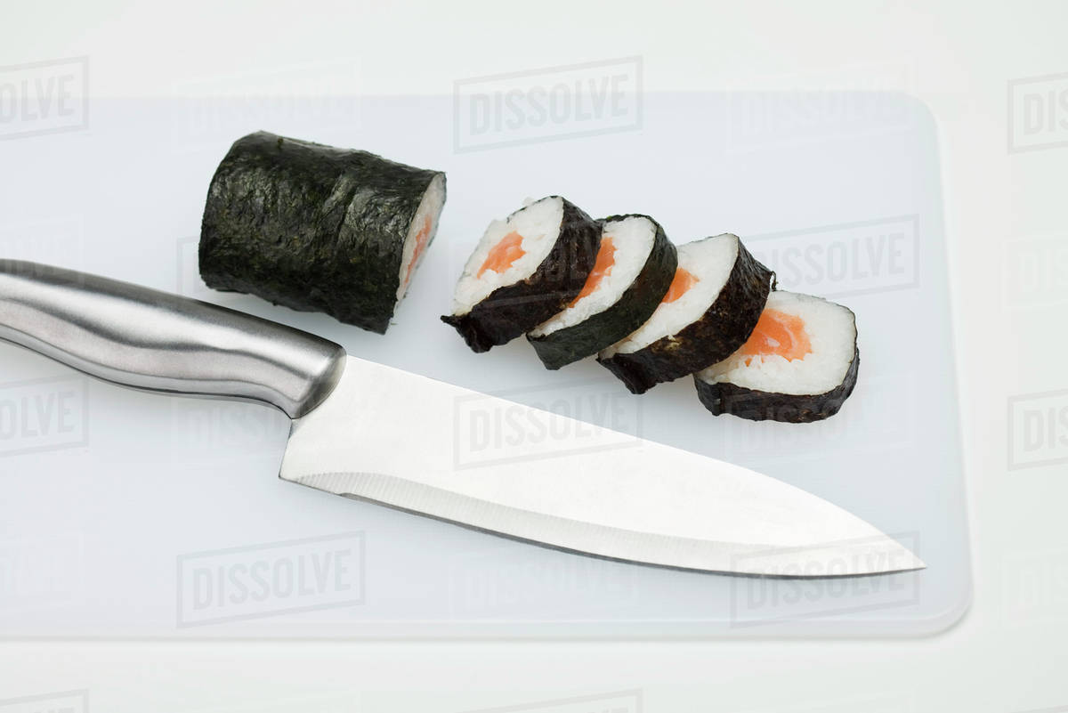 Partially sliced roll of maki sushi on cutting board with knife - Stock ...