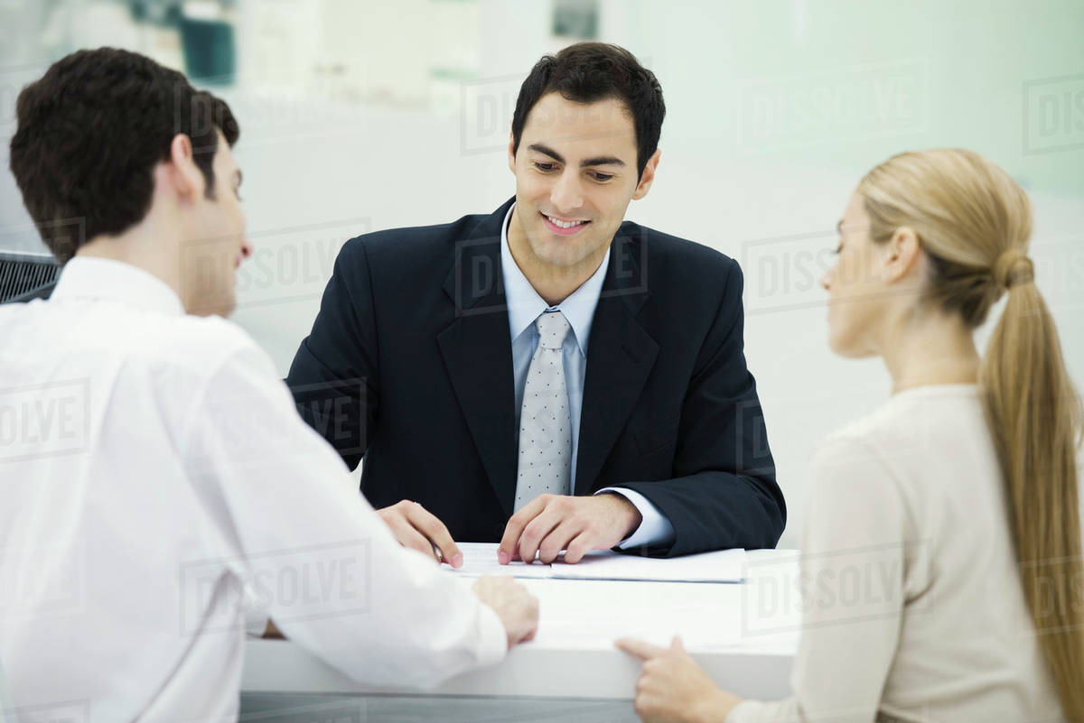 Meeting between professional and clients, together reviewing document ...
