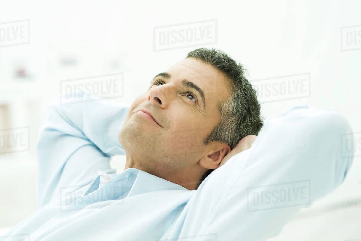 Man leaning back with hands behind head, looking up and smiling ...