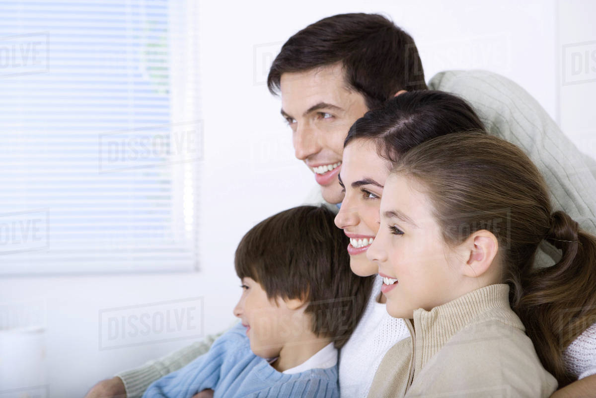 Family smiling at looking away together, side view - Stock Photo - Dissolve
