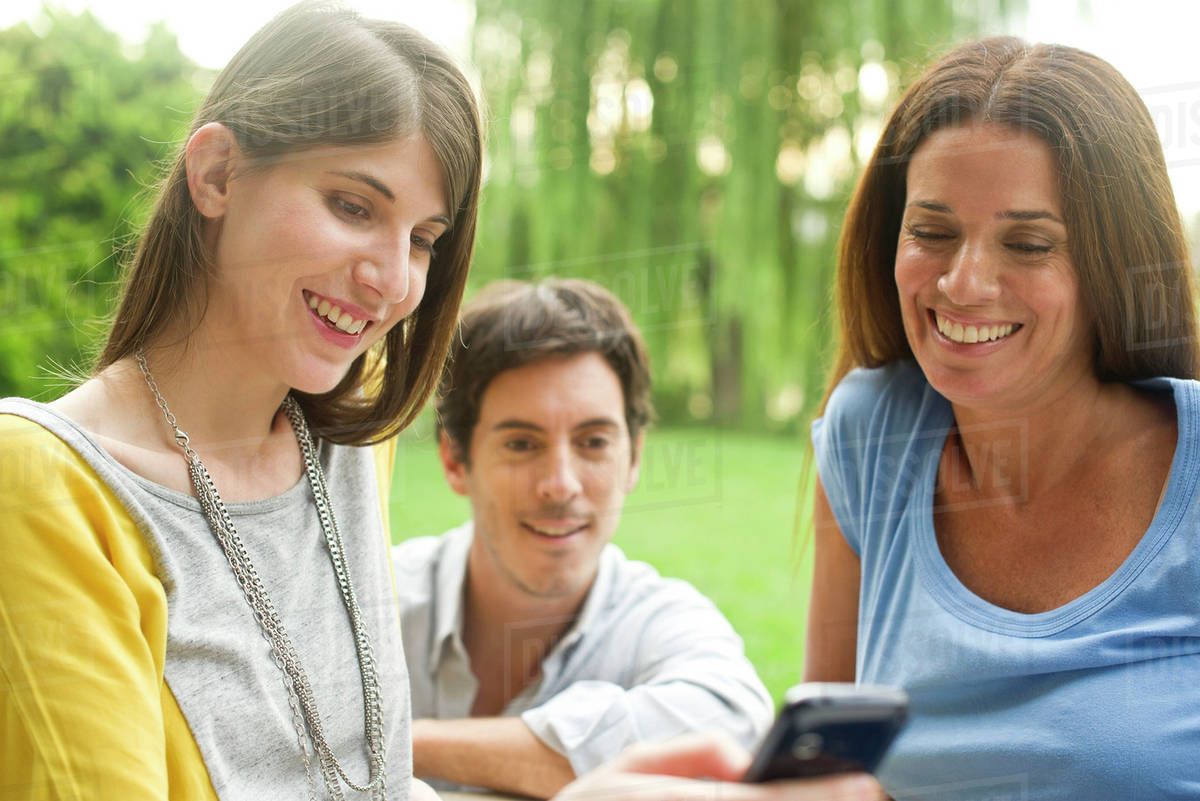 Friends looking at smartphone outdoors - Royalty-free Stock Photo ...