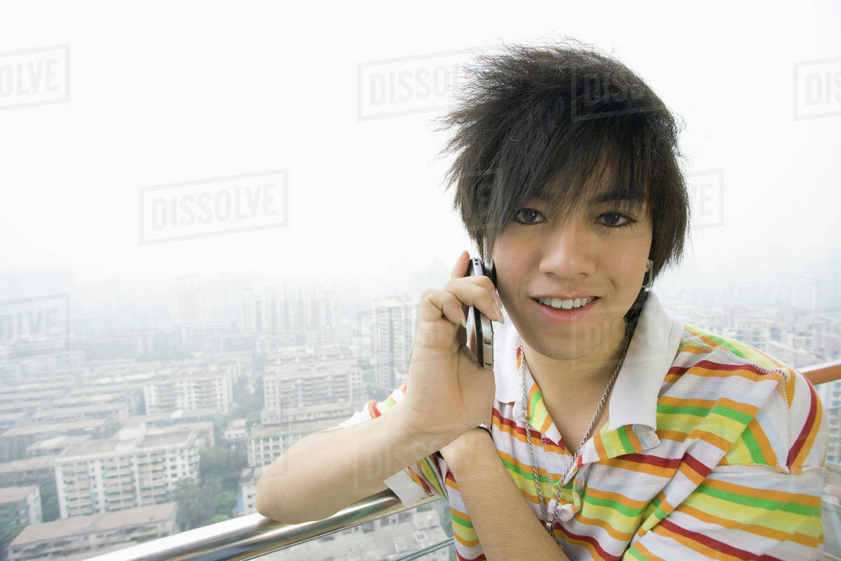 Teenage boy using cell phone, cityscape in background - Royalty-free ...