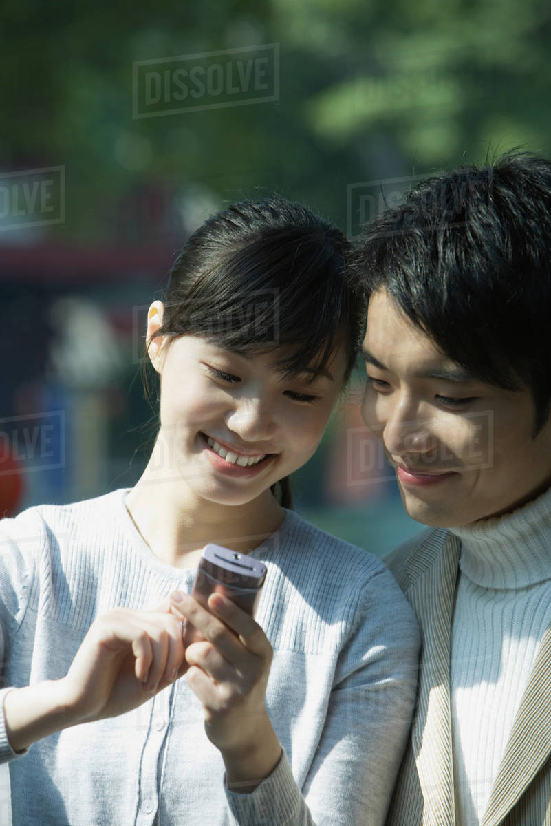 Young couple using cell phone together - Royalty-free Stock Photo ...
