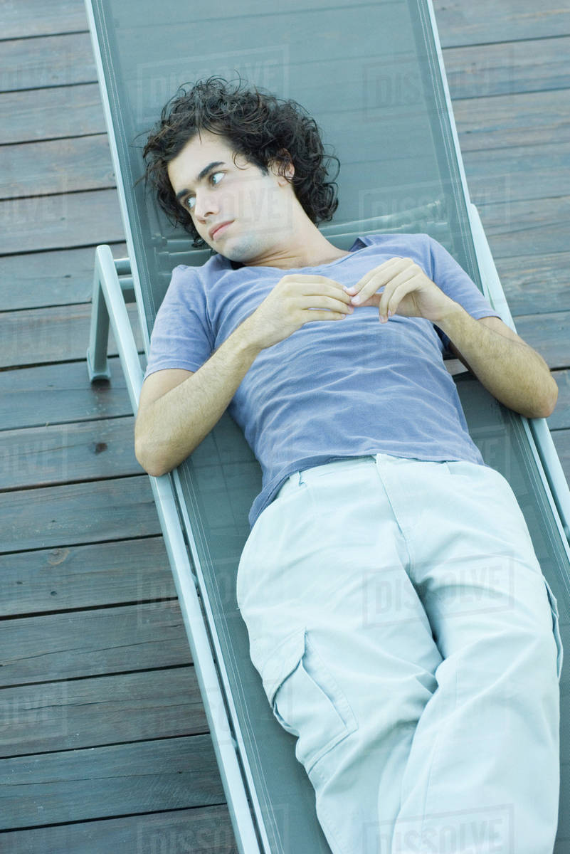 Young man lying on lounge chair - Royalty-free Stock Photo | Dissolve