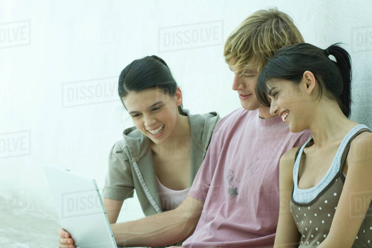 Group of young friends using laptop together - Stock Photo - Dissolve