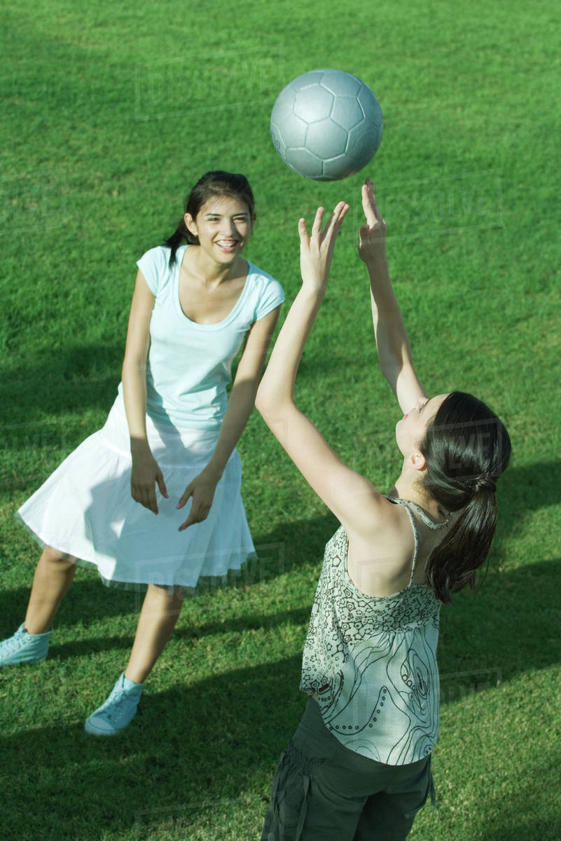 Two young female friends playing with soccer ball - Stock Photo - Dissolve