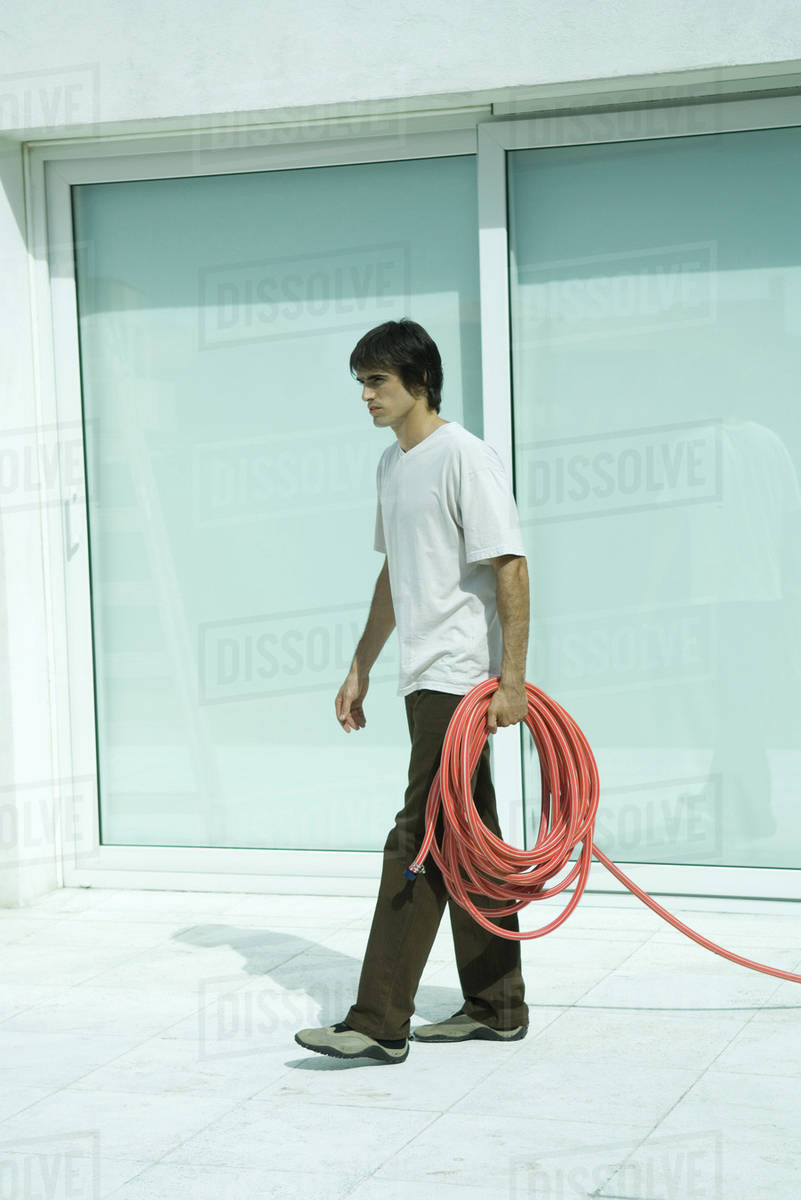 Man carrying garden hose, full length - Royalty-free Stock Photo | Dissolve