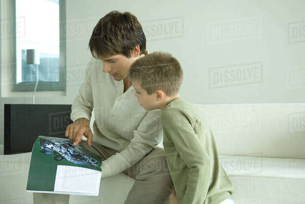 Father and son looking at magazine together - Stock Photo - Dissolve