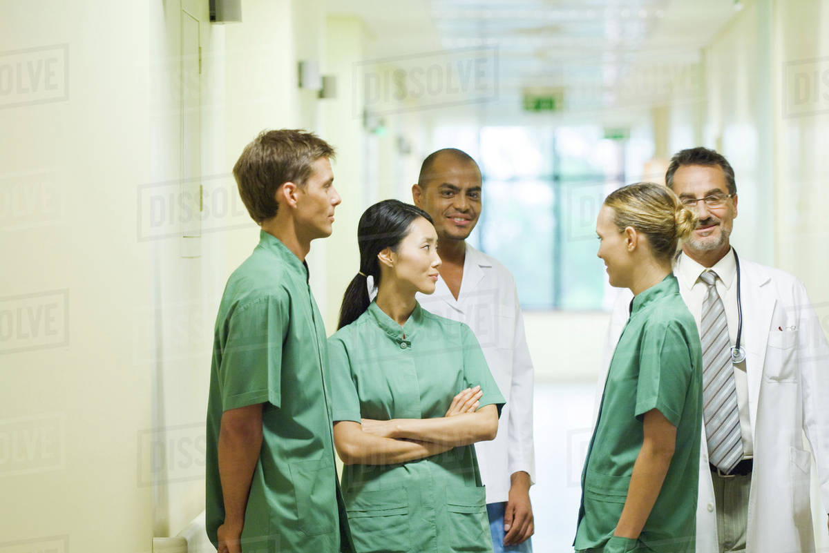 Group of medical staff standing in hallway, chatting, two looking at ...