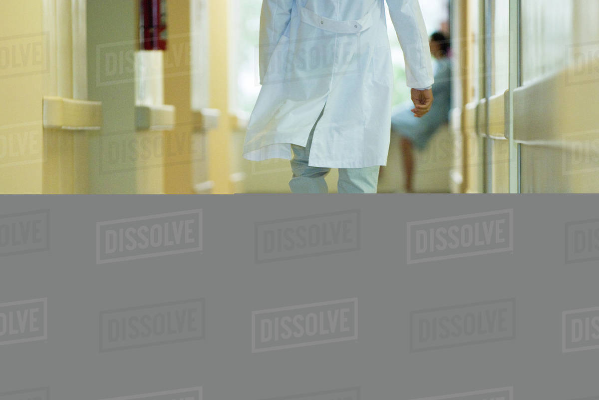 Male doctor walking in hospital corridor, cropped rear view - Royalty ...