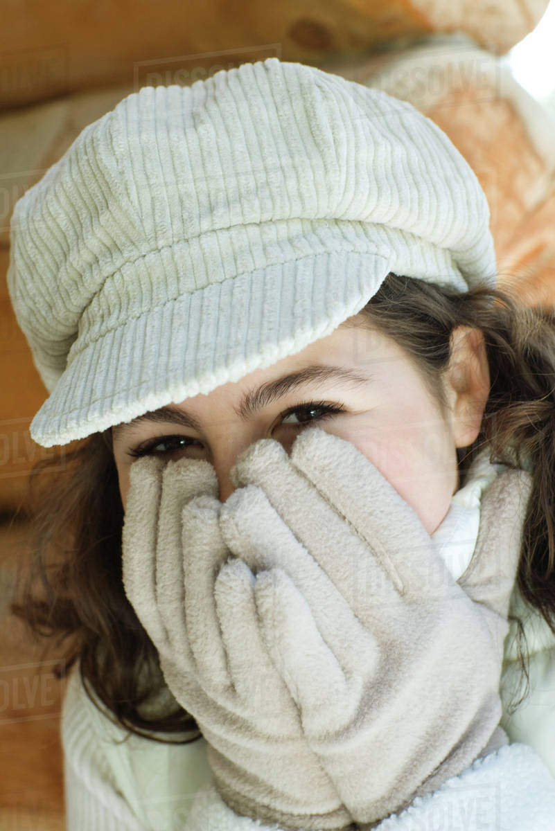 Teenage girl holding gloved hands over mouth, close-up - Royalty-free ...