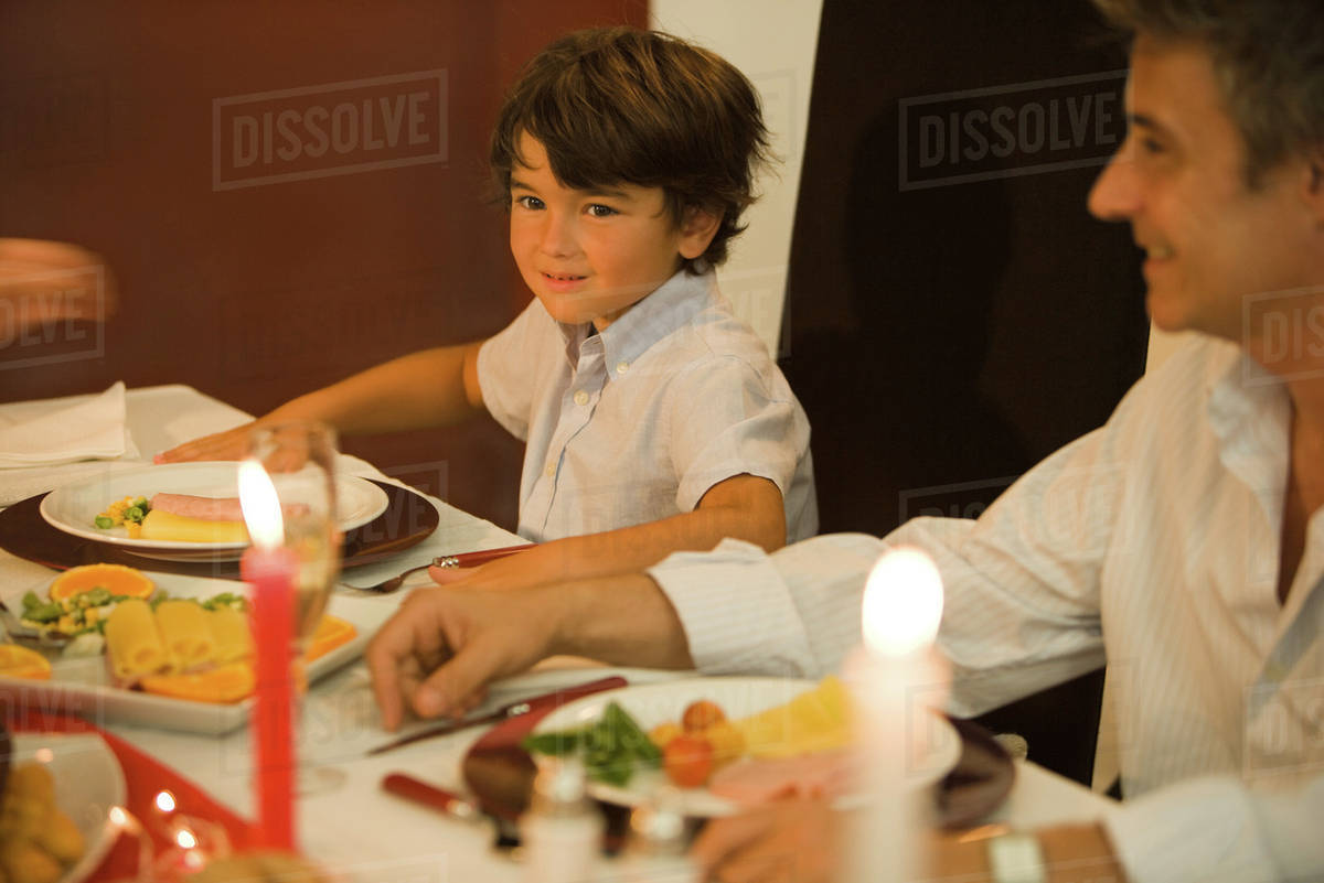 Man and boy sitting at dinner table, smiling - Royalty-free Stock Photo ...