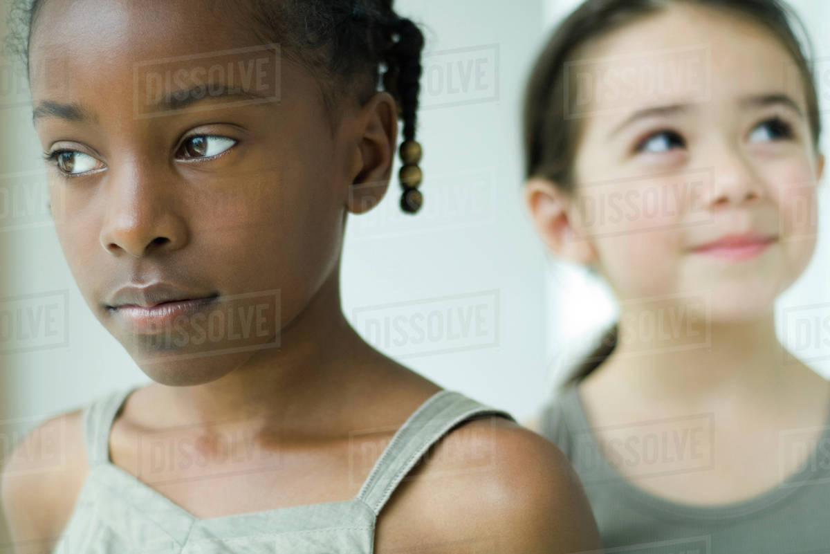 Close-up of girl looking away, friend looking up and smiling in ...