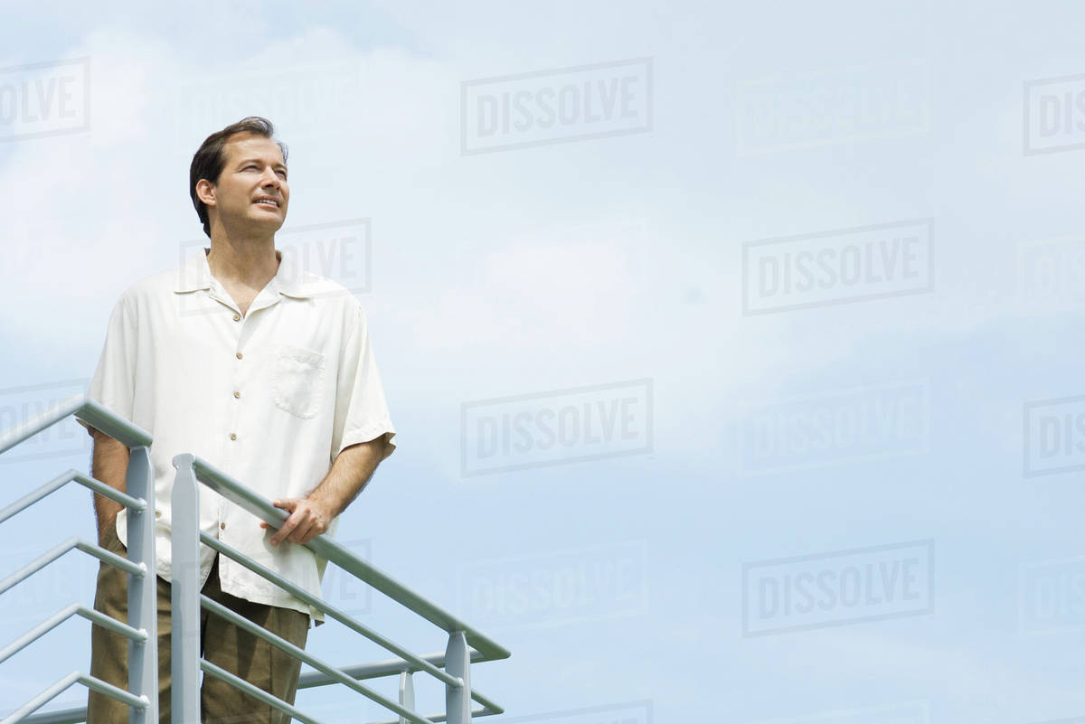 Man standing on balcony, looking away, smiling - Royalty-free Stock ...