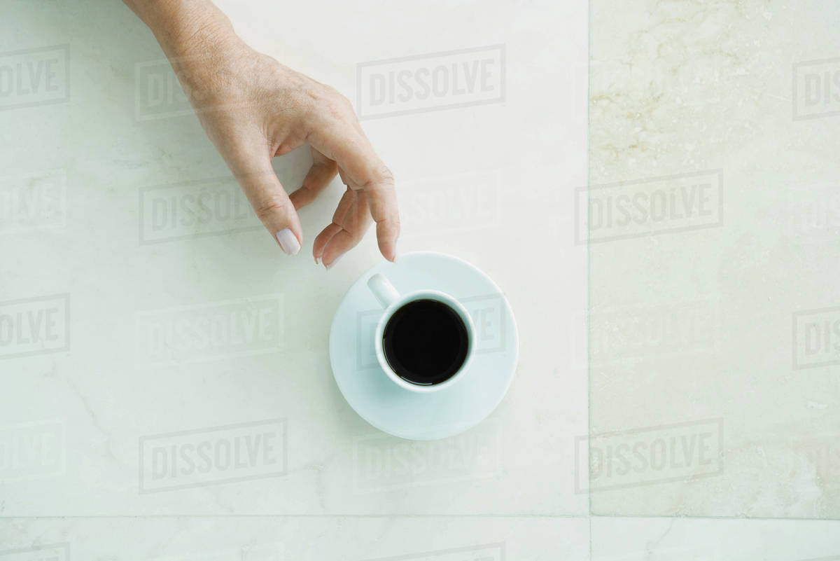 Hand reaching for coffee cup, viewed from directly above - Royalty-free ...
