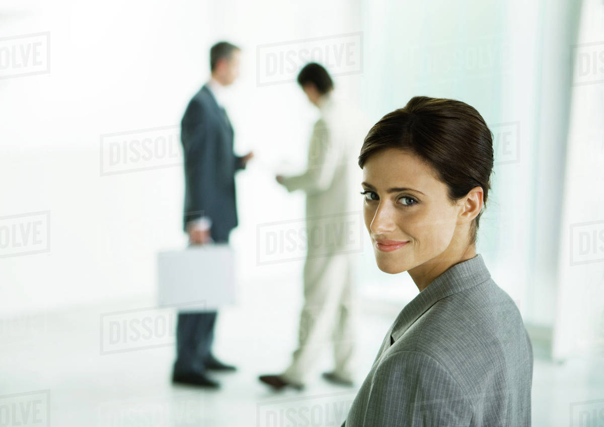 Businesswoman looking over shoulder in office lobby - Royalty-free ...