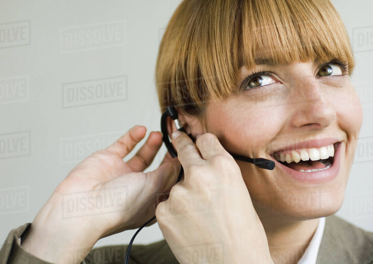 Woman smiling and putting on headset - Royalty-free Stock Photo | Dissolve