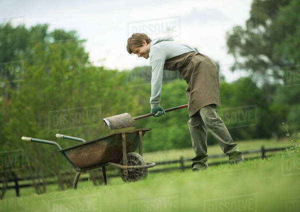 Man shoveling dirt into wheelbarrow - Royalty-free Stock Photo | Dissolve