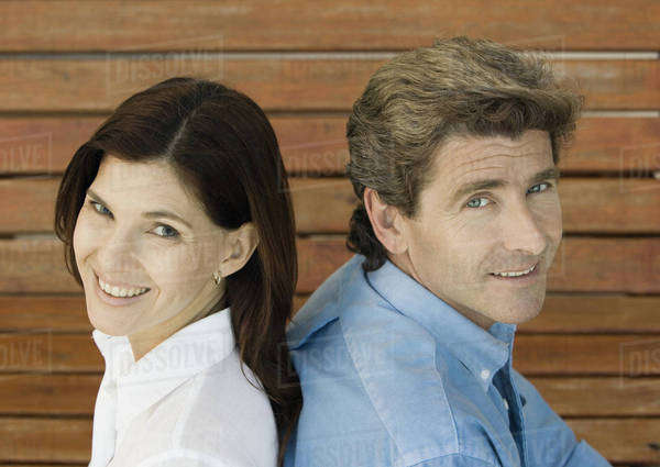 Couple back to back, smiling and looking at camera, portrait, close-up ...