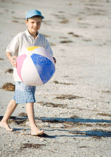 Boy carrying beach ball on beach - Royalty-free Stock Photo | Dissolve