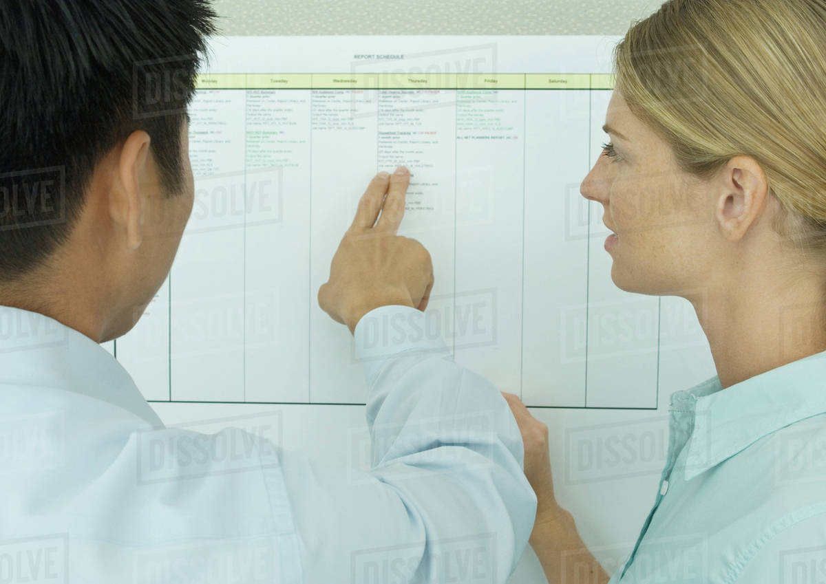 Two colleagues looking at chart on wall - Stock Photo - Dissolve