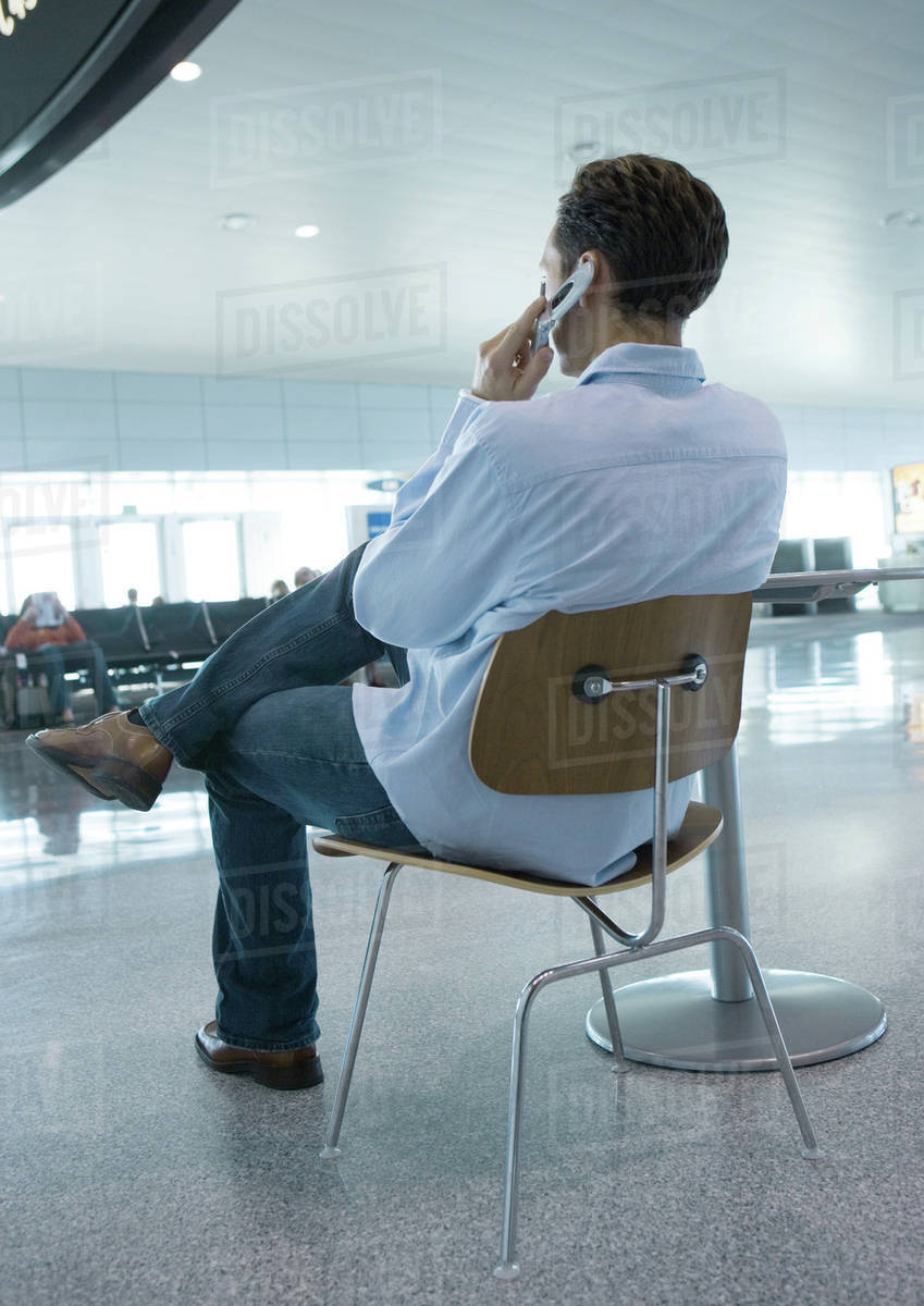 Man sitting in chair using cell phone - Stock Photo - Dissolve