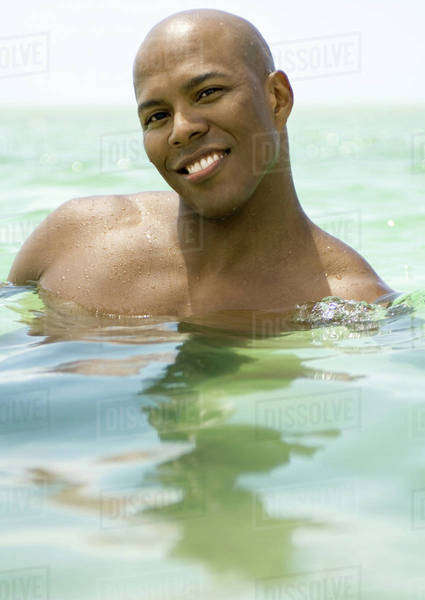 Man wading in sea, smiling - Royalty-free Stock Photo | Dissolve