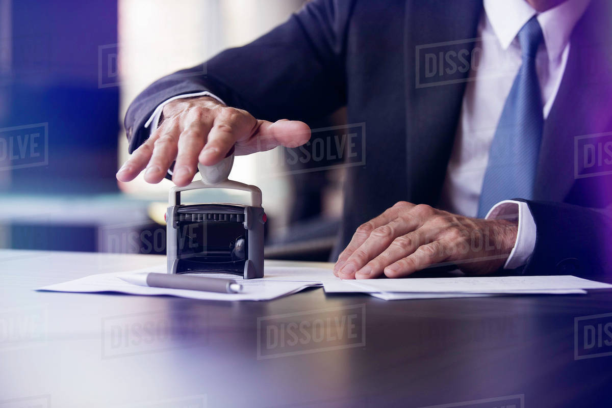 Businessman stamping document - Royalty-free Stock Photo | Dissolve