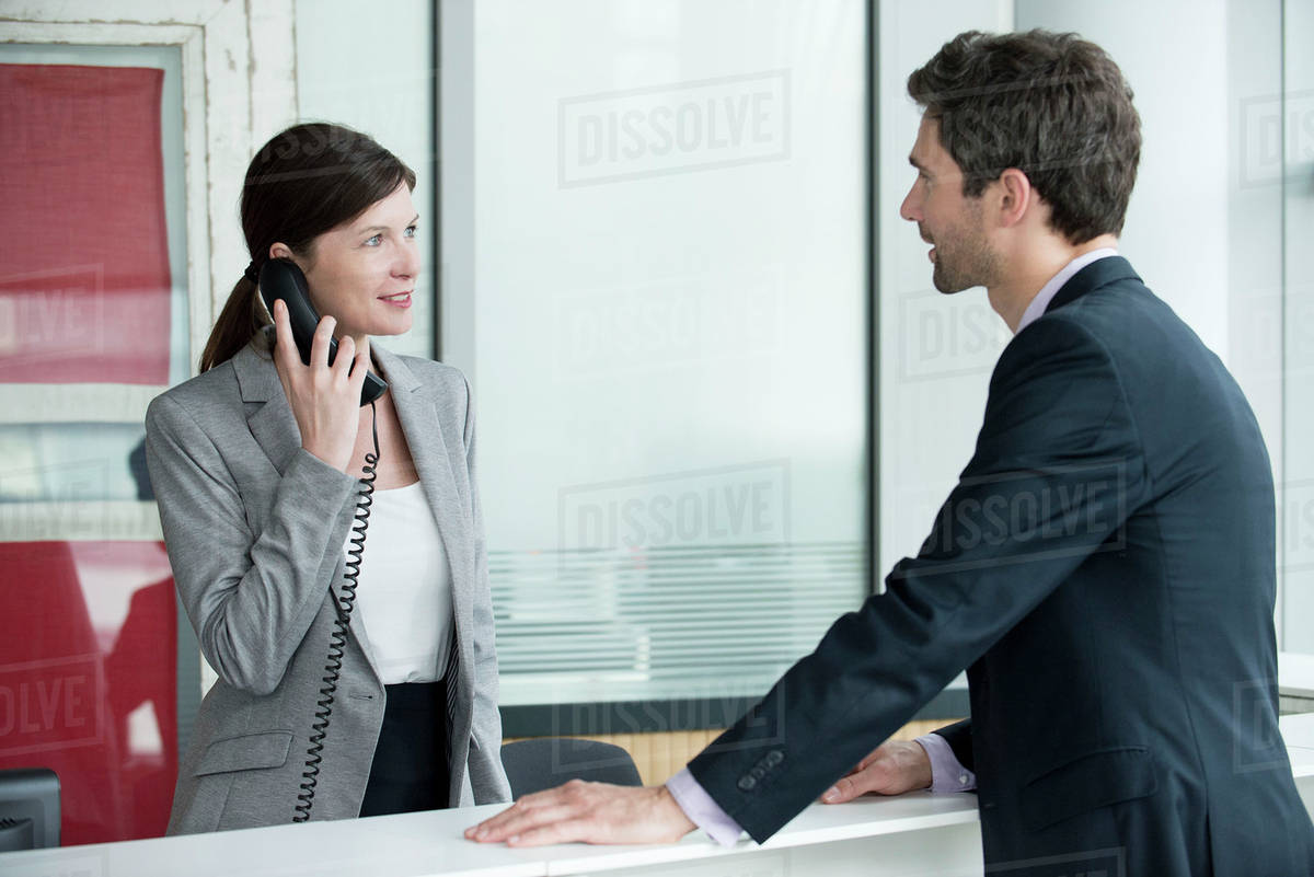 Hotel reception staff helping guest - Royalty-free Stock Photo | Dissolve