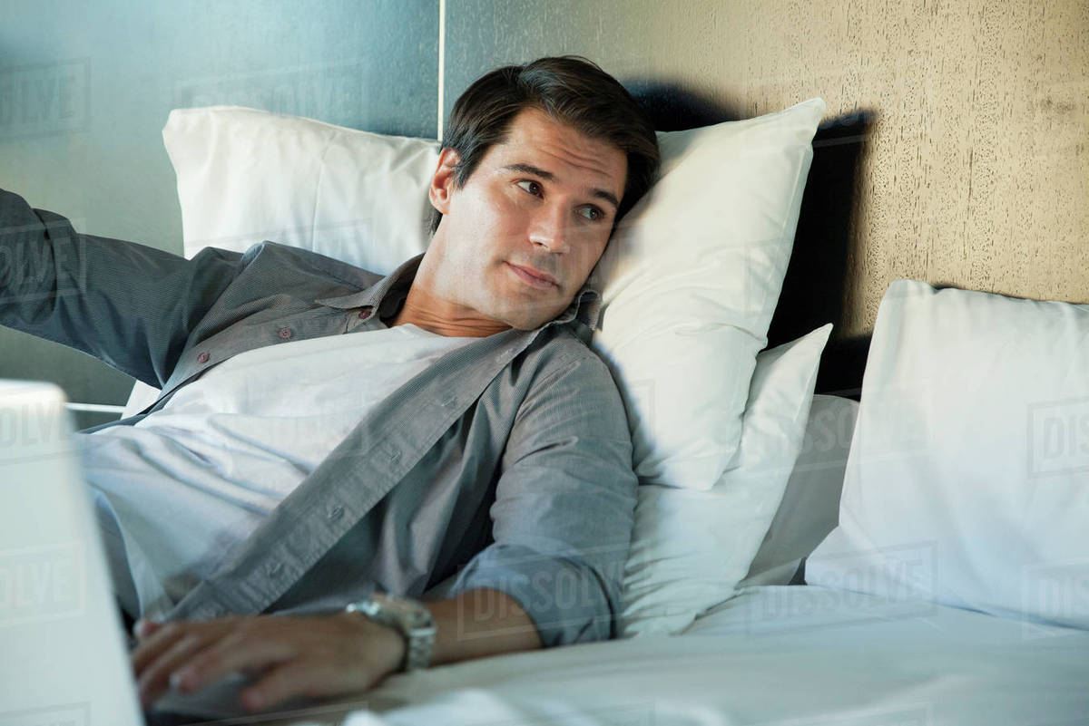 Man relaxing in bed with laptop computer - Royalty-free Stock Photo ...