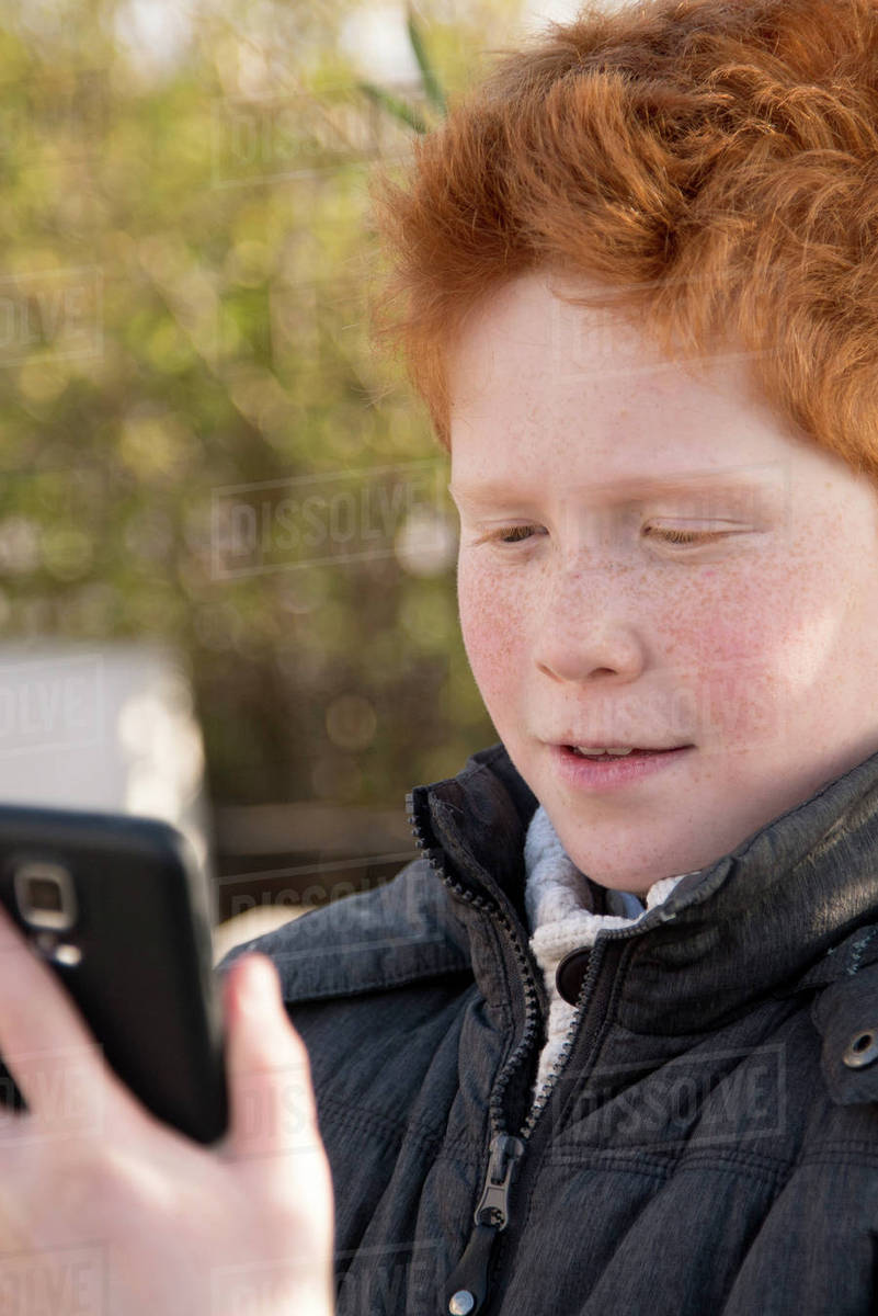 Boy using smartphone outdoors - Royalty-free Stock Photo | Dissolve