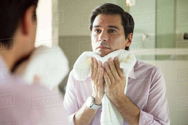 Man looking in mirror, drying his face with a towel - Royalty-free ...