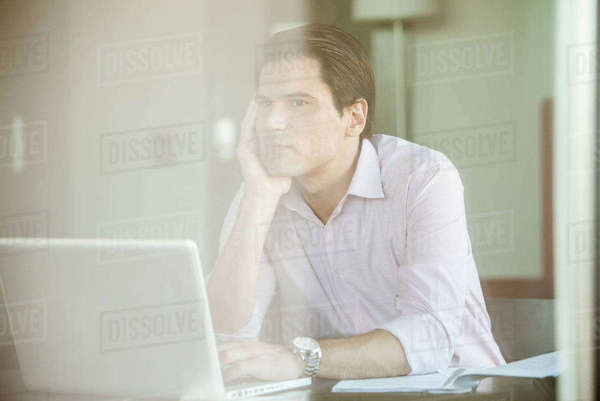 Man sitting before laptop computer, daydreaming in office - Royalty ...