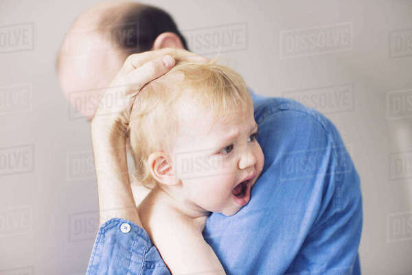 Father comforting crying baby - Stock Photo - Dissolve