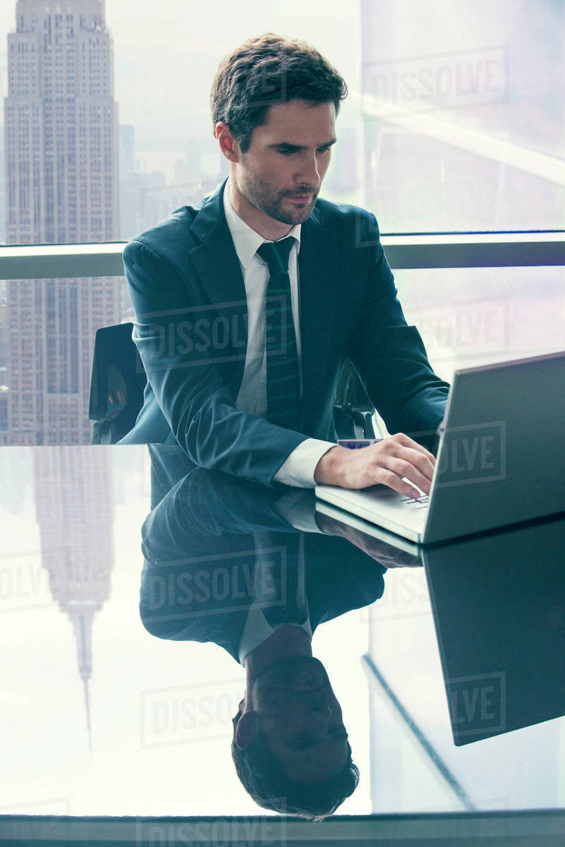 Businessman using laptop computer alone at conference table - Royalty ...