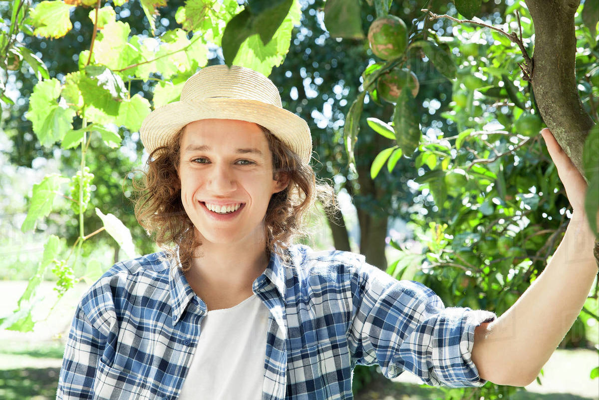 Young man standing under tree in vineyard, portrait - Royalty-free ...