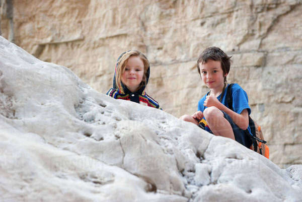Children crouching on rock - Stock Photo - Dissolve