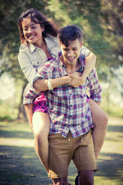 Man giving girlfriend piggyback ride in park - Stock Photo - Dissolve