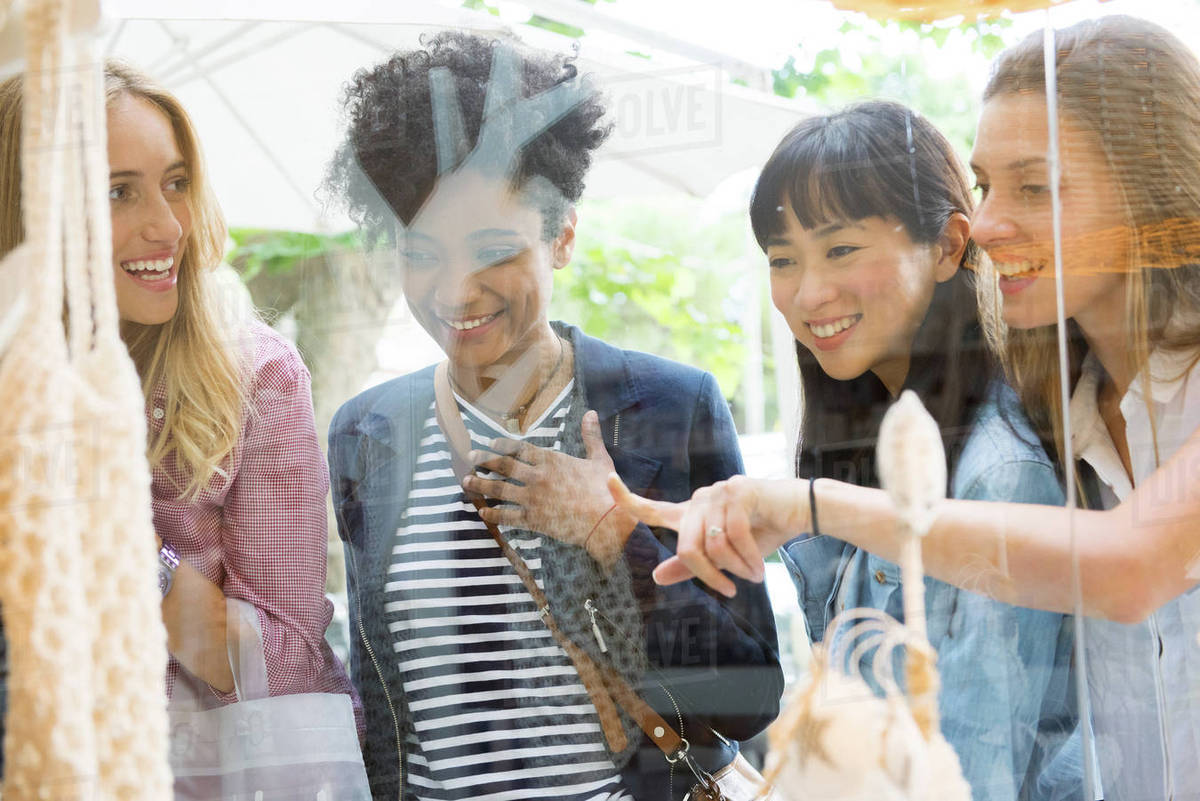 Young women looking through shop window together - Stock Photo - Dissolve