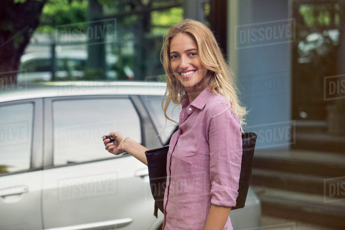 Woman approaching car with key in hand, smiling over shoulder - Royalty ...