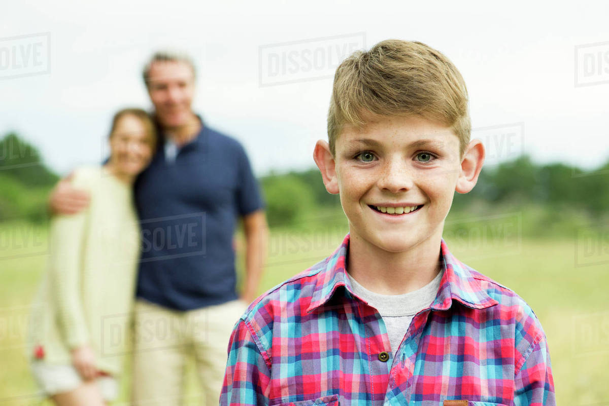 Boy with parents in background, portrait - Stock Photo - Dissolve