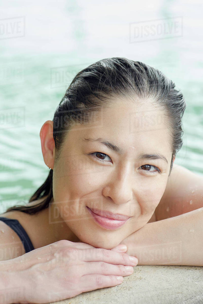 Woman at side of swimming pool resting head on arms - Stock Photo ...