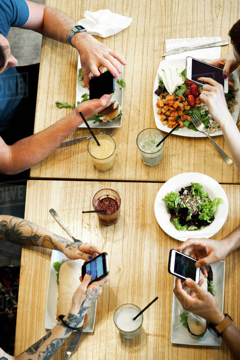 Diners using smartphones in restaurant, cropped overhead view - Royalty ...