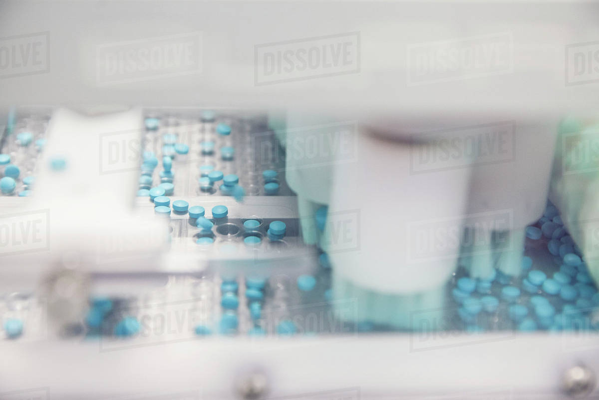 Pills dropping onto plastic trays in blisterpack sealing machine ...