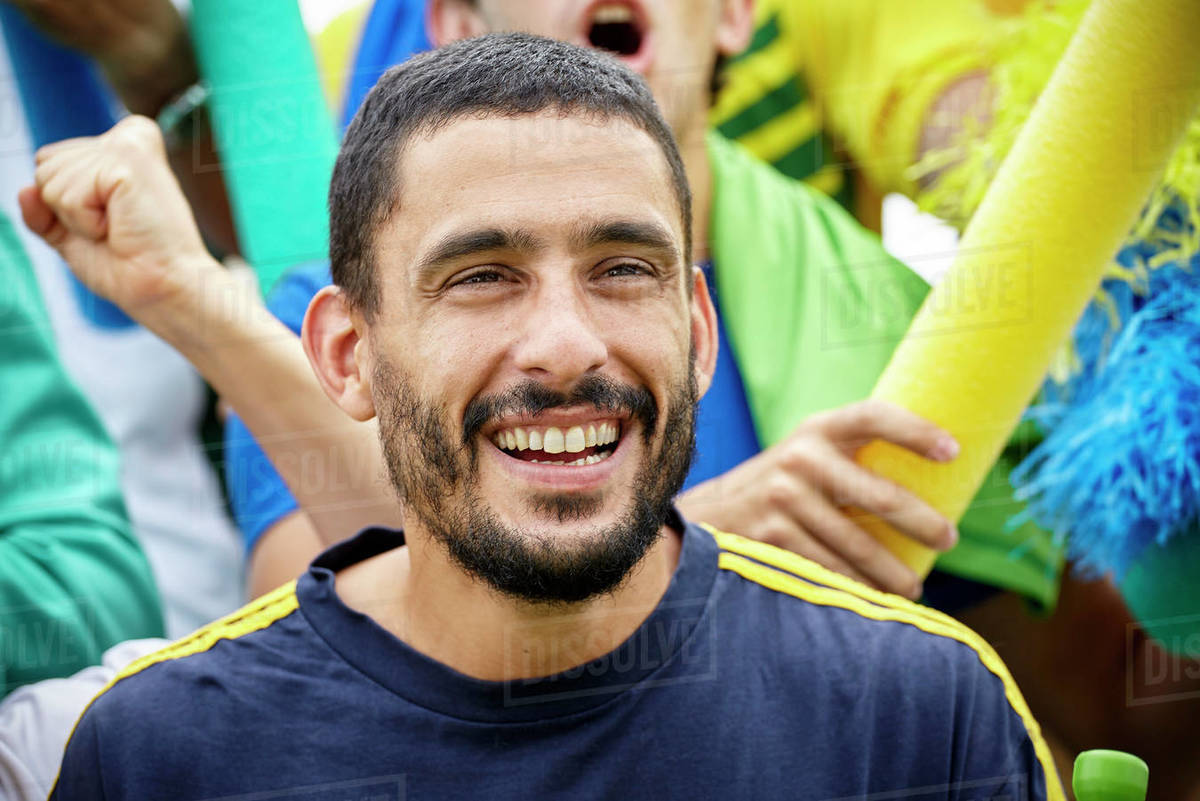 Man smiling cheerfully at football match, portrait - Stock Photo - Dissolve