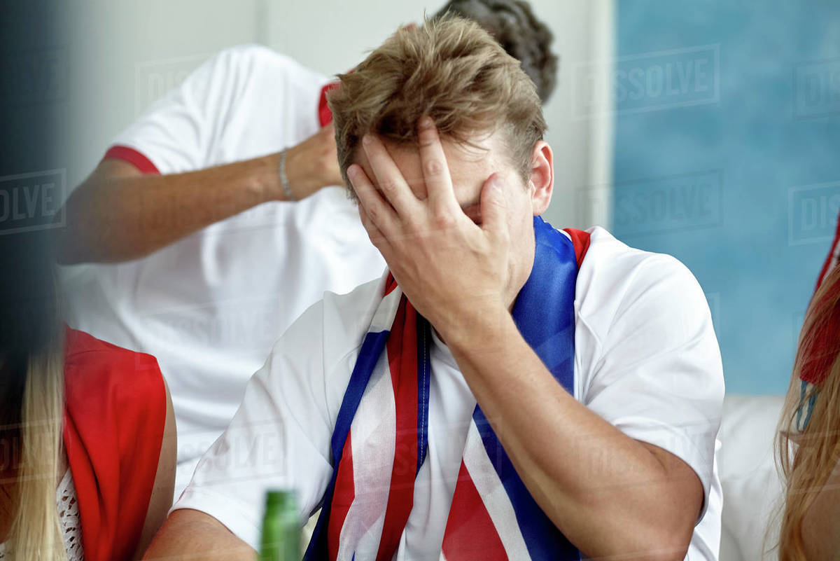 British football fan covering face with hand while watching match ...